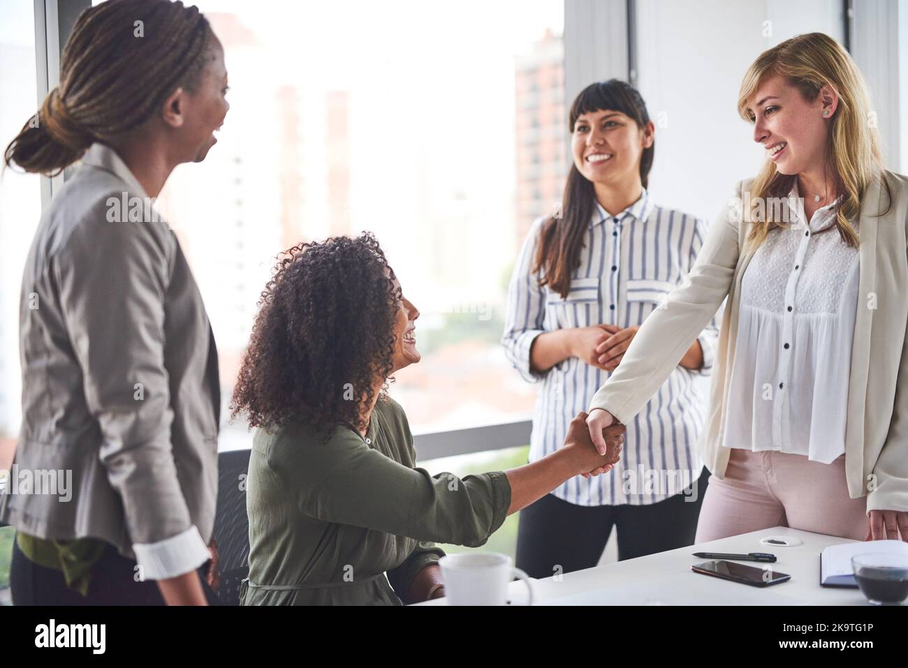 Welcome to our team. a group of businesswomen shaking hands in the office Stock Photo - Alamy