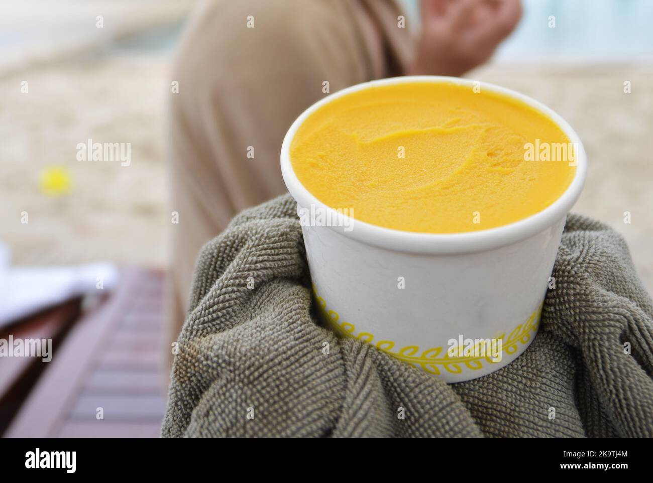 Silky smooth Mango sorbet in a cup wrapped by a pool side beach towel ...
