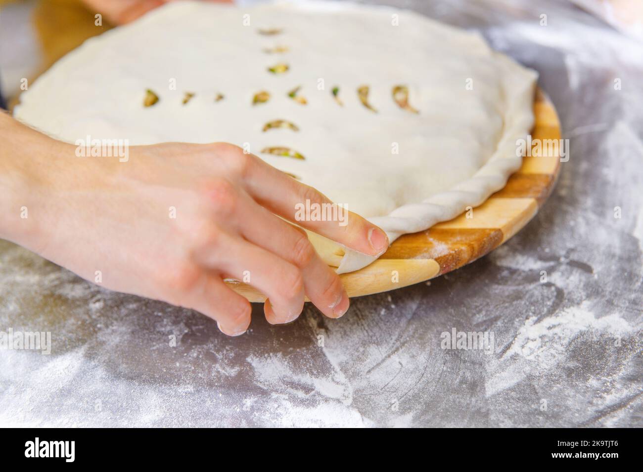Hands closing the Ossetian pie stuffed with minced meat on the metal ...