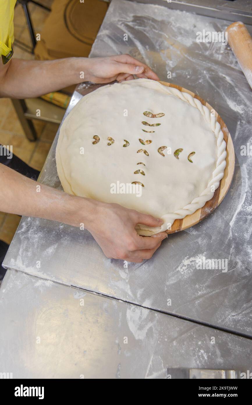 Hands closing the Ossetian pie stuffed with minced meat on the metal ...