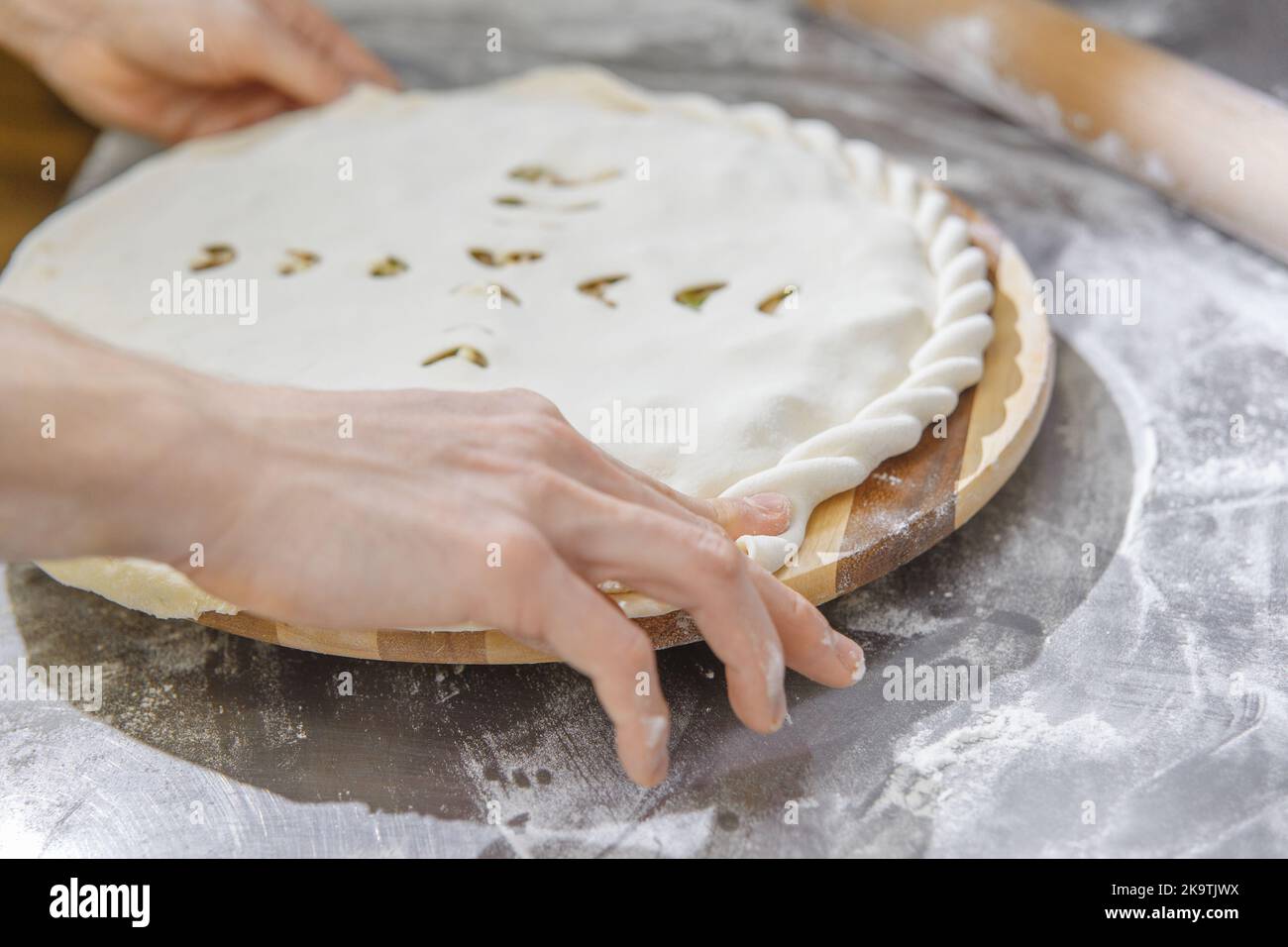 Hands closing the Ossetian pie stuffed with minced meat on the metal ...