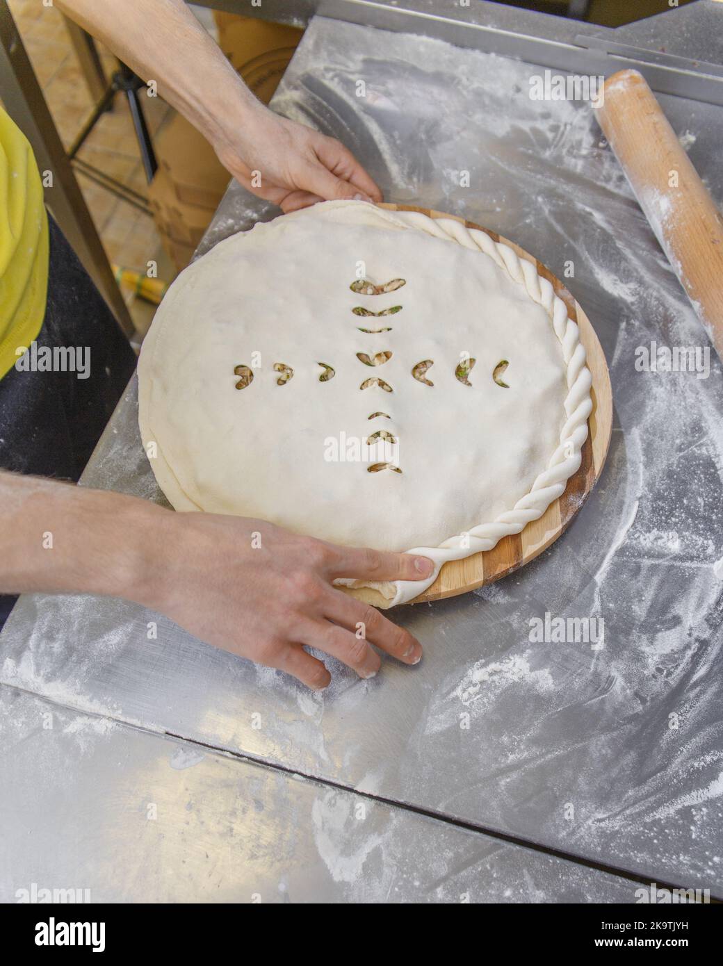 Hands closing the Ossetian pie stuffed with minced meat on the metal ...