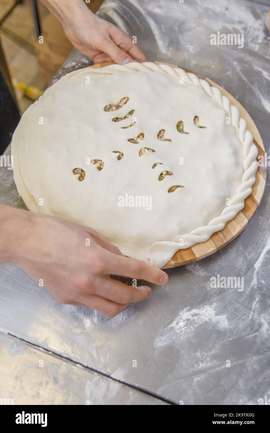 Hands closing the Ossetian pie stuffed with minced meat on the metal ...