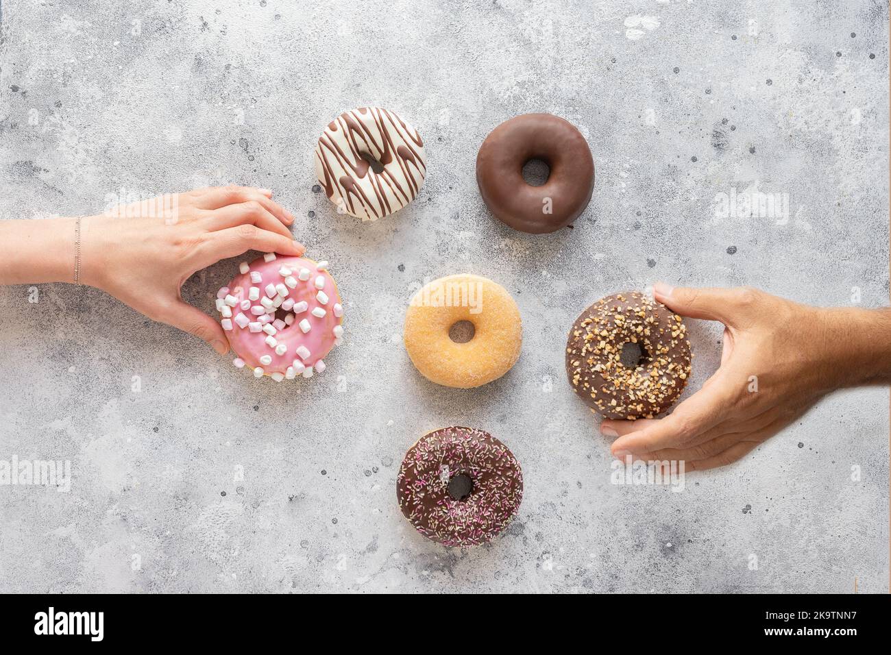 Hands holding fresh donuts on grey background with copy space ...