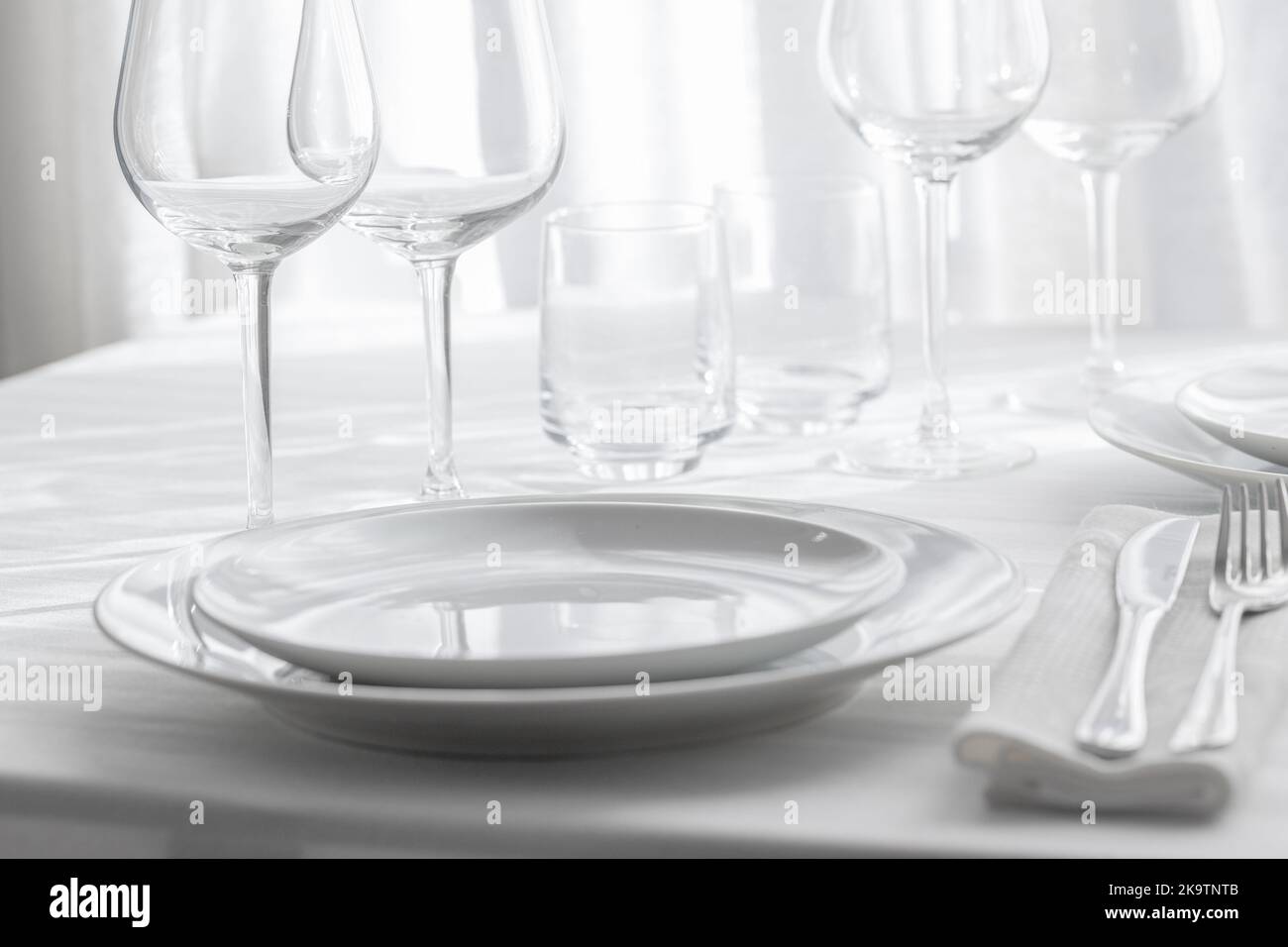 Table setting white and grey colour. Empty glasses and plates set with ...