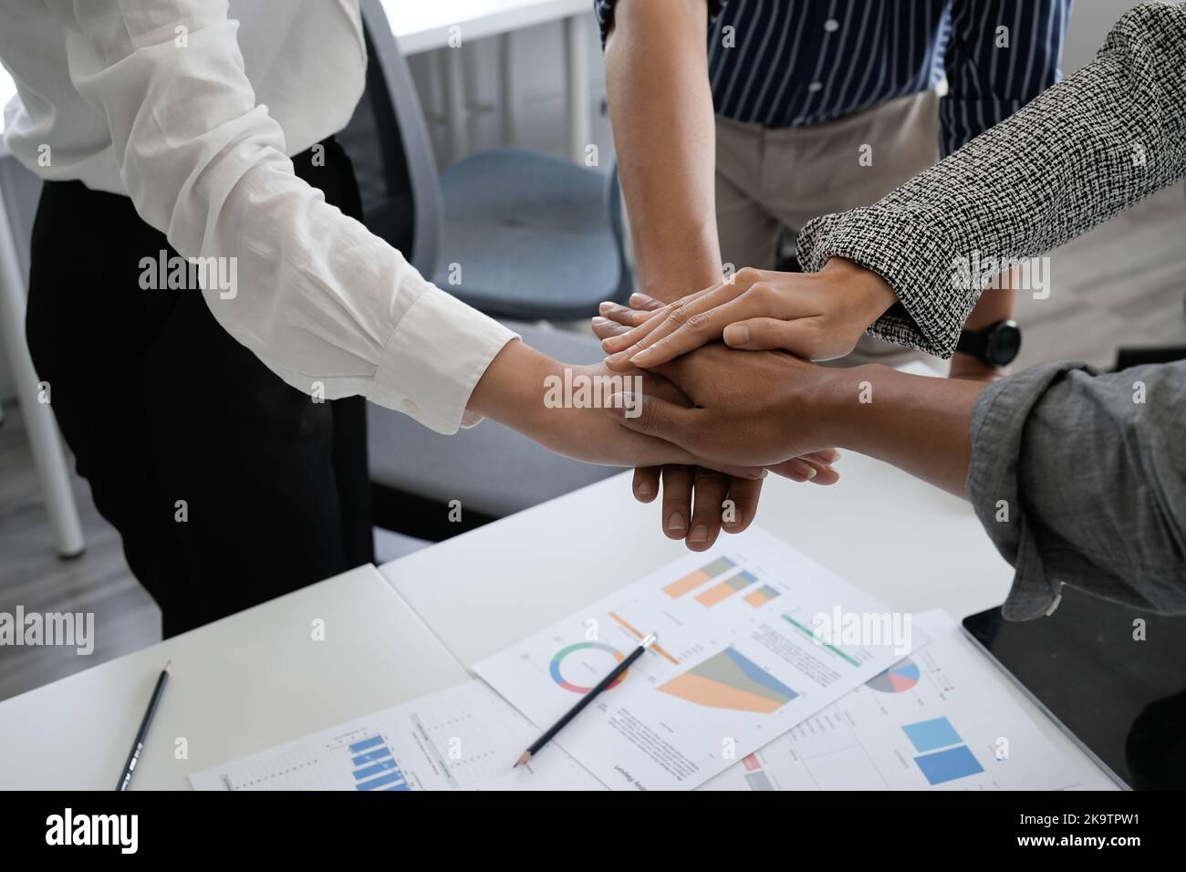 Close up happy diverse business people putting hands together, showing support and unity ...