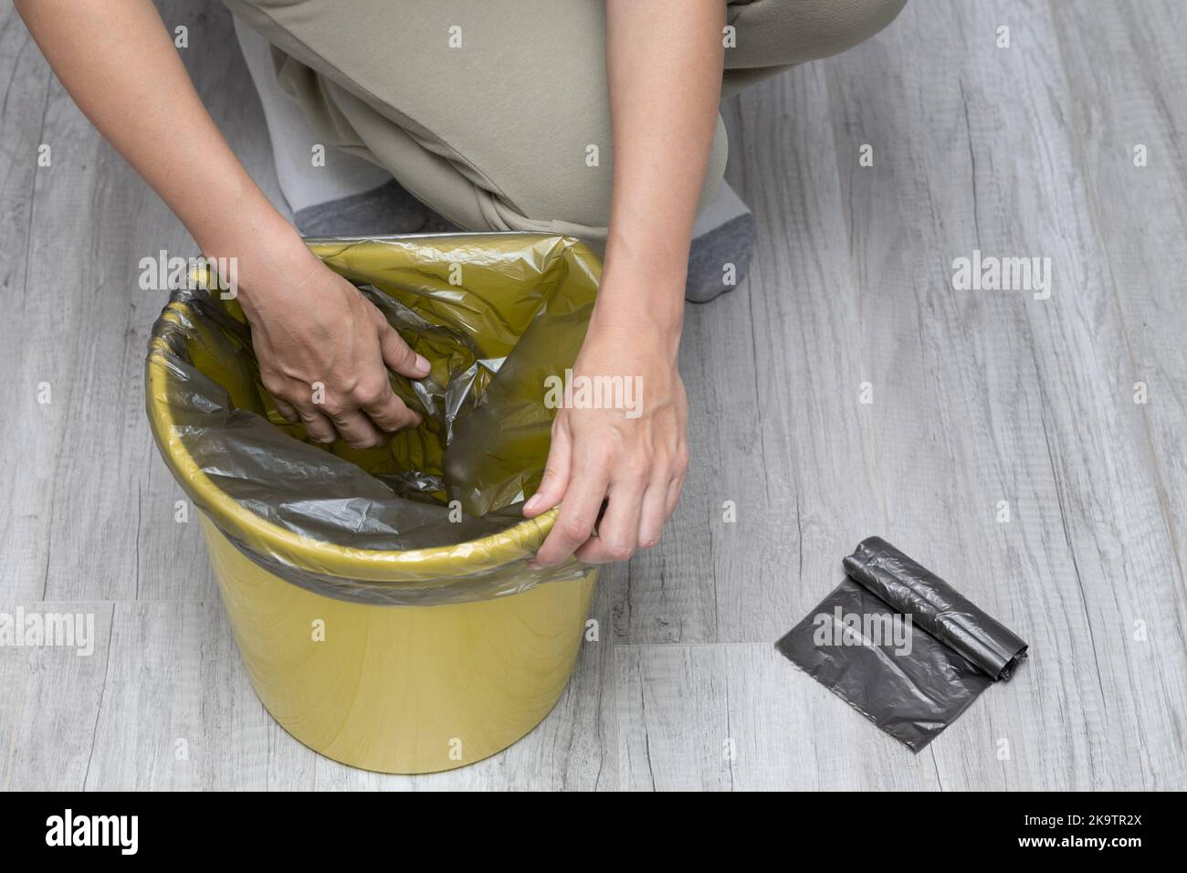 a woman changes a garbage bag in a bucket. woman tearing off a trash ...