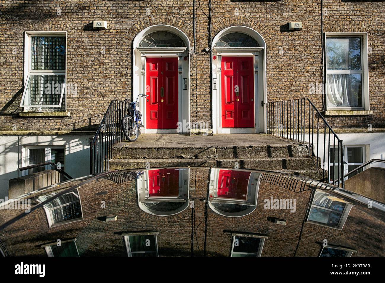 Typical terraced houses, two red doors reflected on a car roof, Dublin ...
