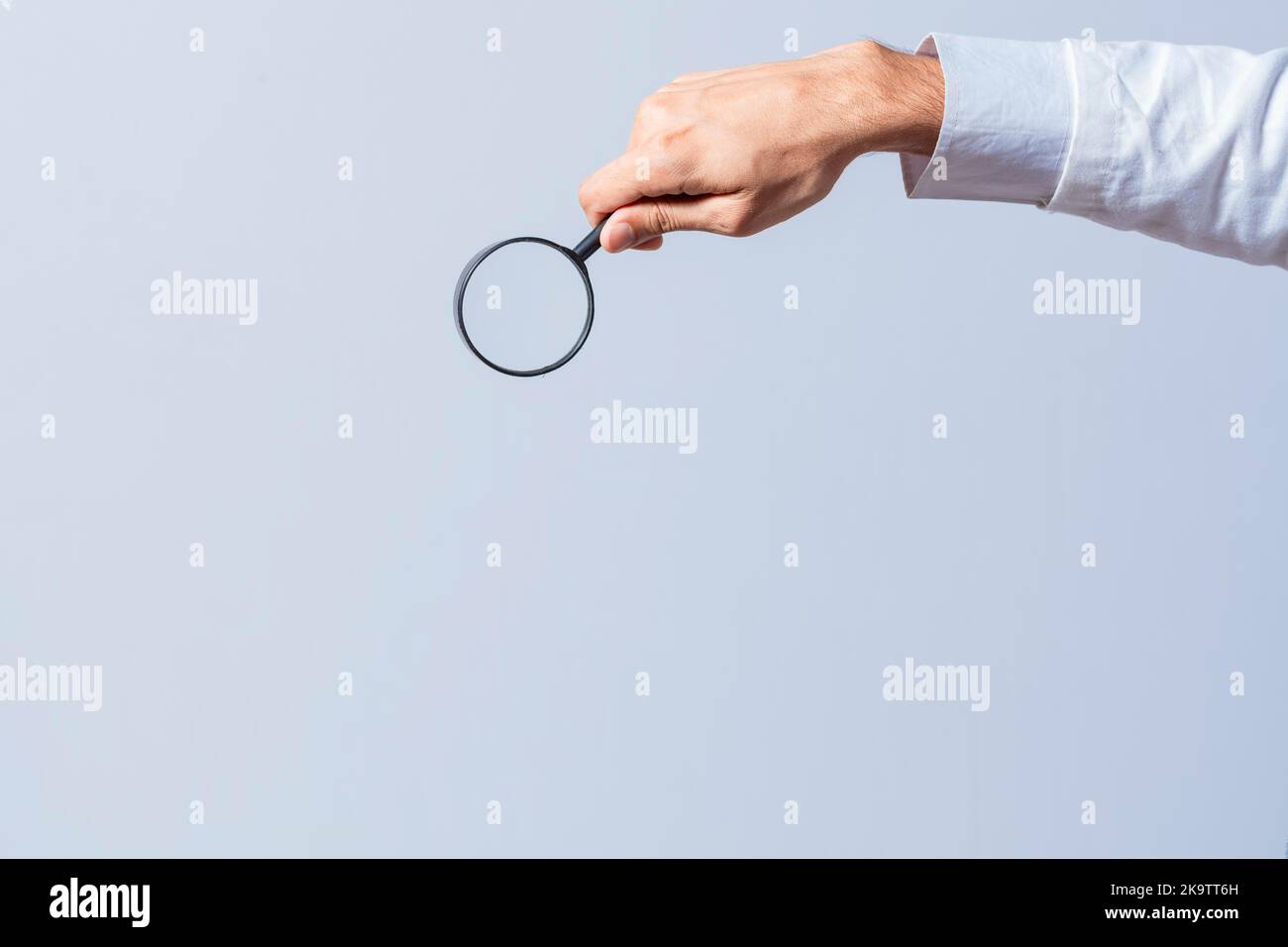 Hand holding magnifying glass on isolated background. Man's hand ...
