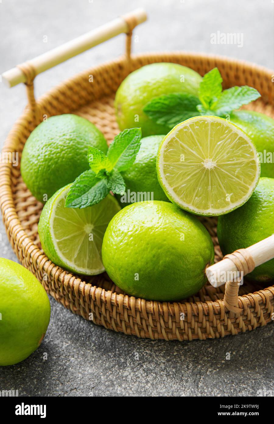 Green Limes with fresh mint leaves on wicker tray, concrete background Stock Photo - Alamy