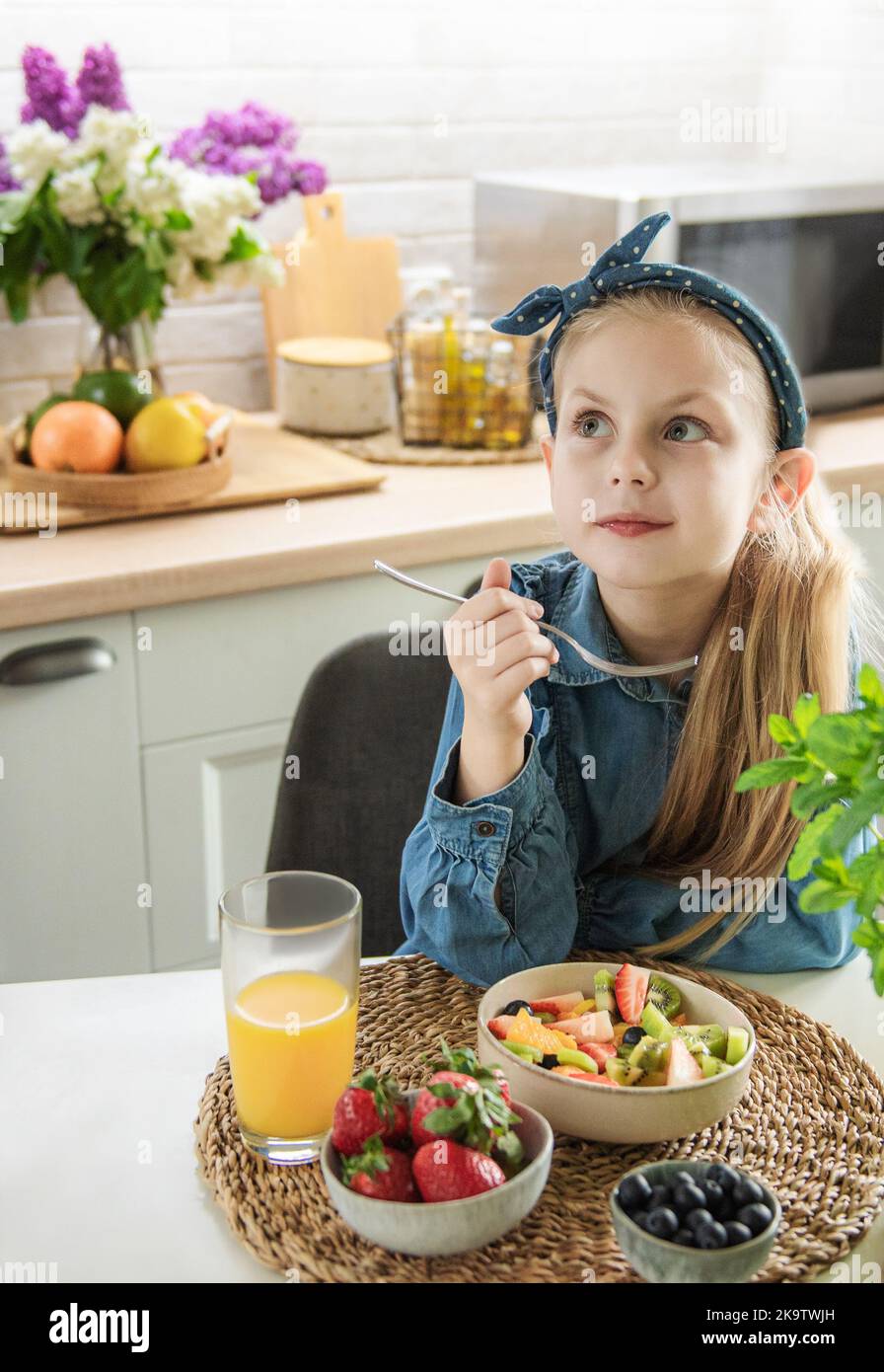 Healthy food at home. Cute little girl eats fruit salad Stock Photo - Alamy