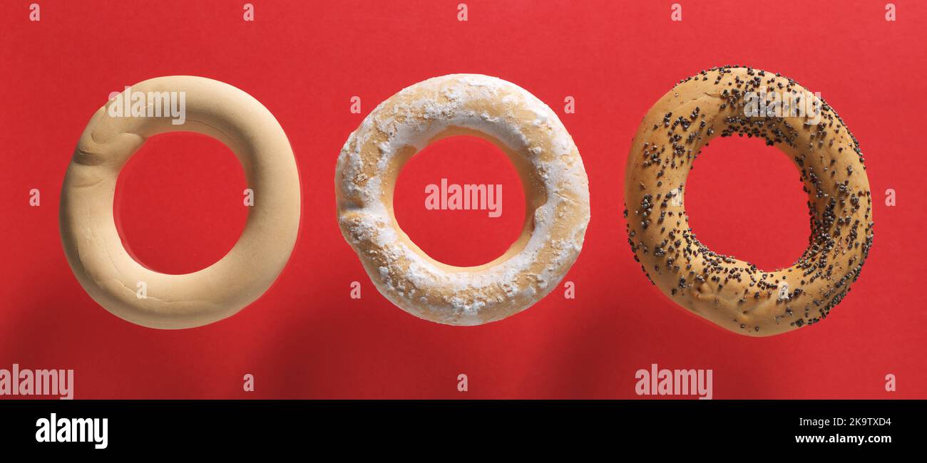 Three different bagels on a red background, top view Stock Photo - Alamy