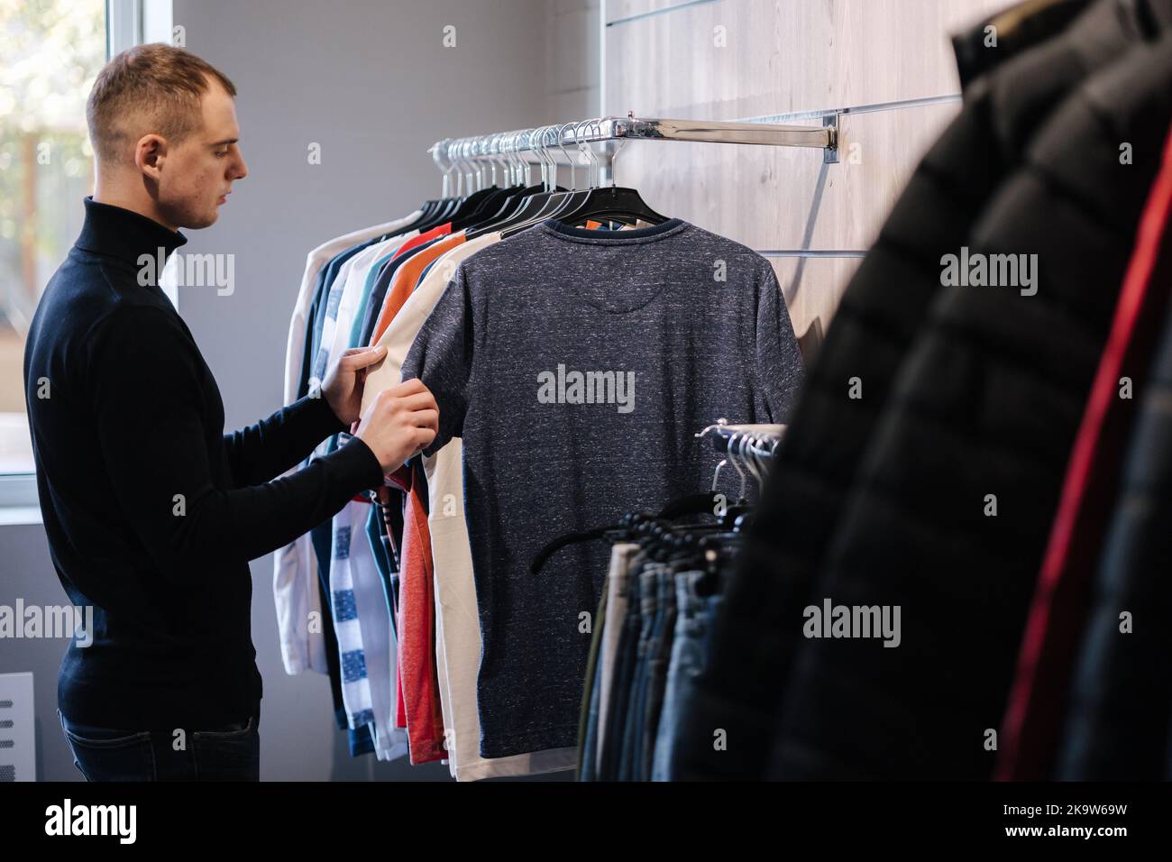 Half body shot of handsome customer choosing clothes. Man choose shirt ...