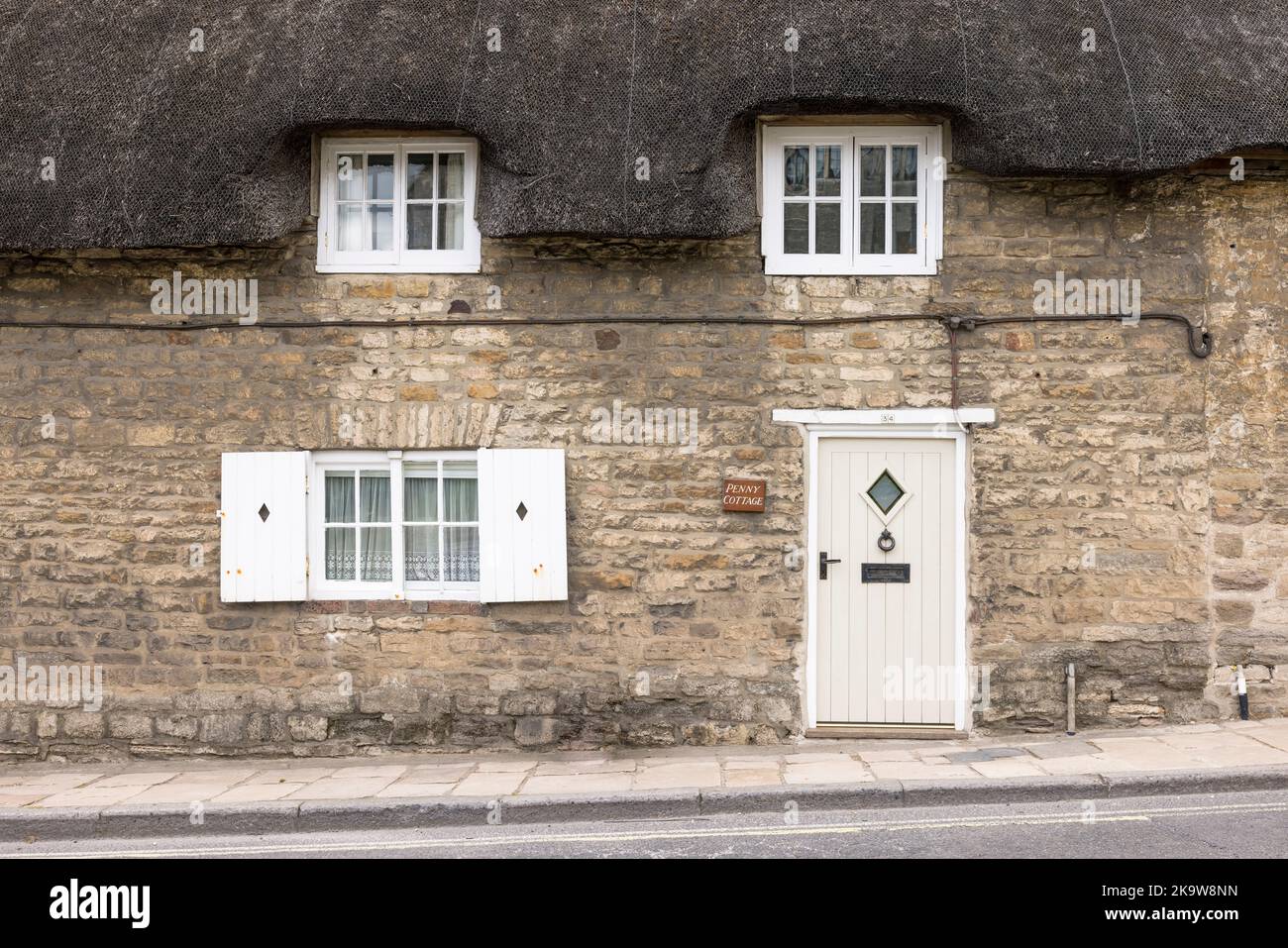 DORSET, UK - July 06, 2022. Front of a stone thatched cottage on a ...