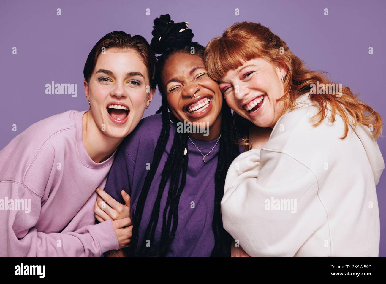 Three best friends smiling at the camera while standing against a ...