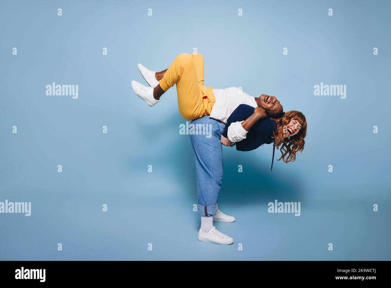 Energetic young woman carrying her best friend on her back in a studio ...