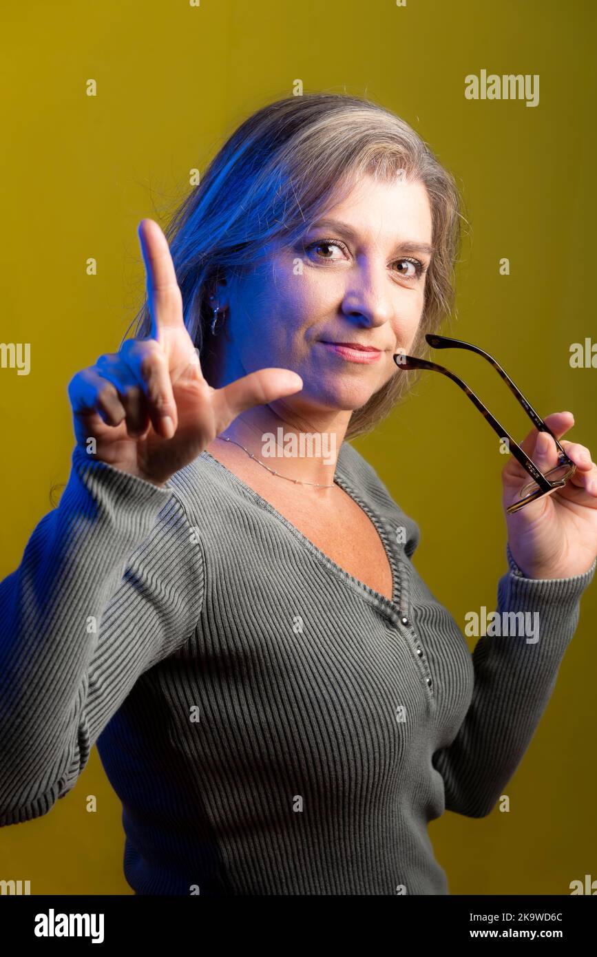 Portrait of model wearing eyeglasses against yellow background. She ...