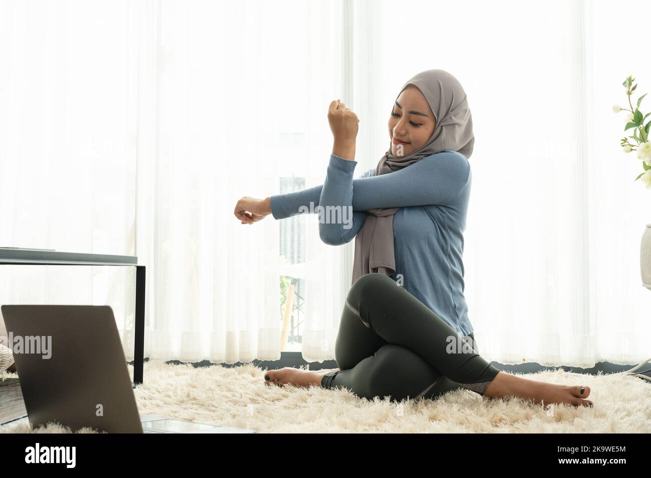 Asian young woman is practicing yoga in the livingroom. A Muslim woman ...