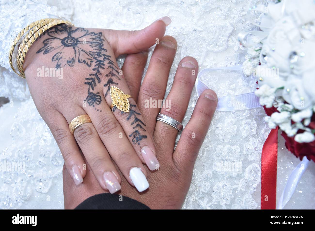 Hands of newlyweds with wedding rings and bridal bouquet. Henna drawing ...