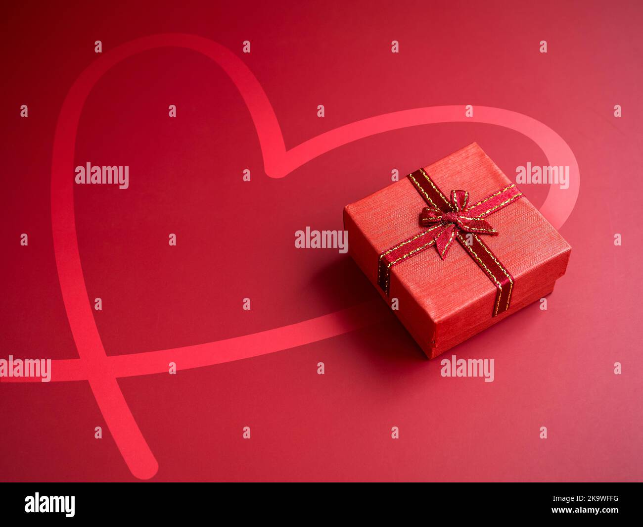 A small red present gift box with ribbon on heart shape drawing red ...