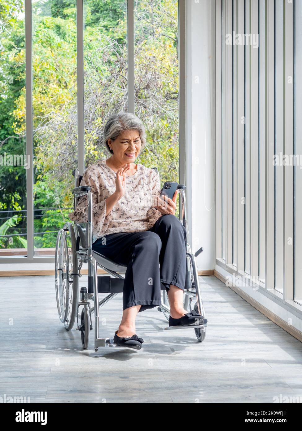 Happy Asian senior woman sits in wheelchair, waving greetings, smile ...