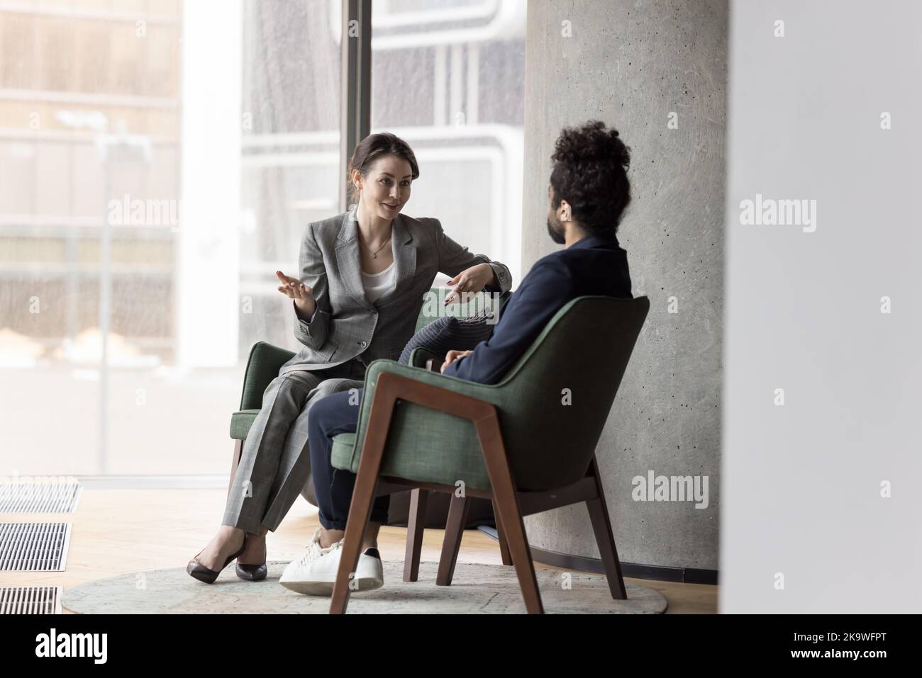 Workmates talking seated on cozy armchairs in modern office lobby Stock ...
