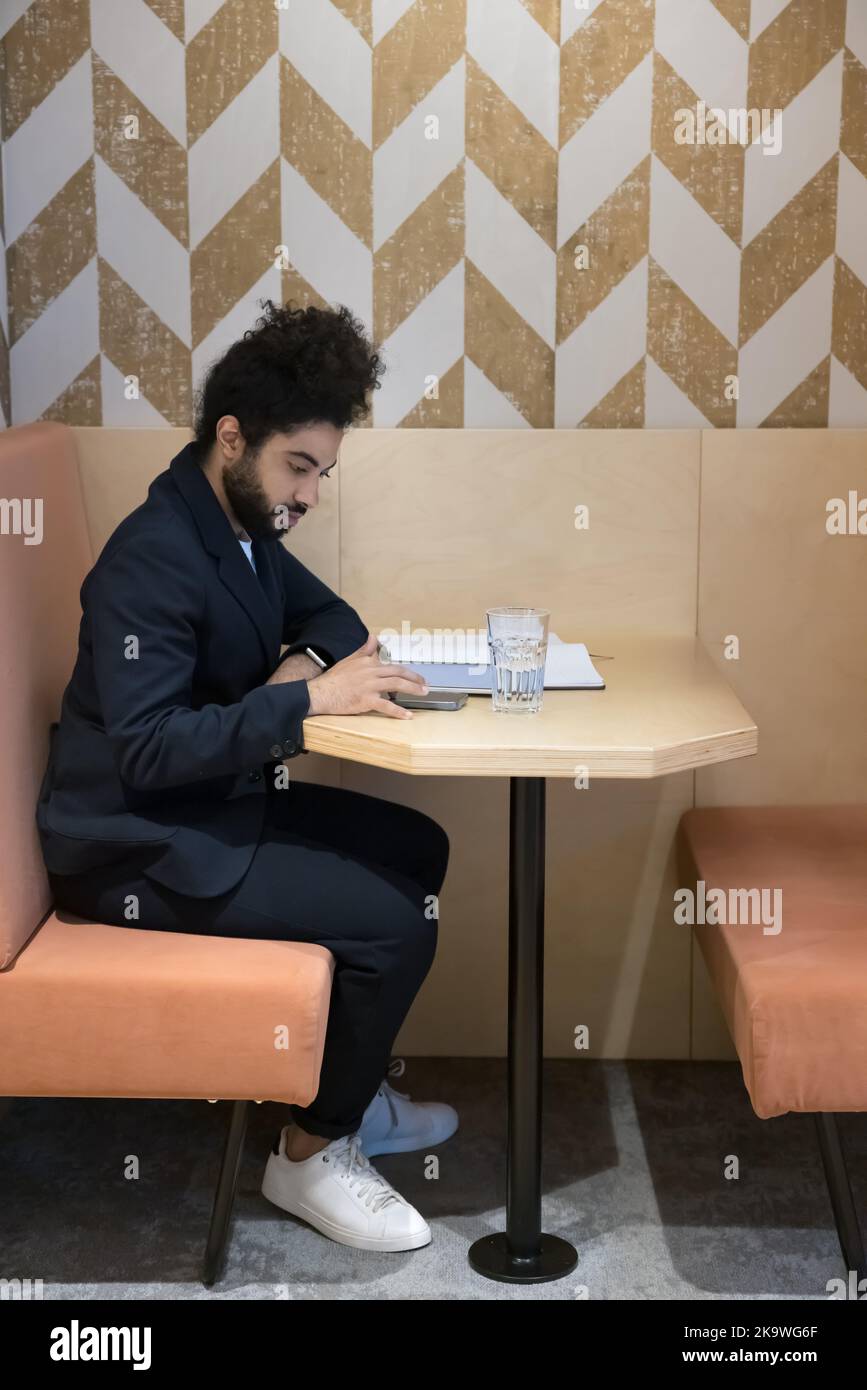 Indian man in formal suit use smartphone seated in coworking Stock ...