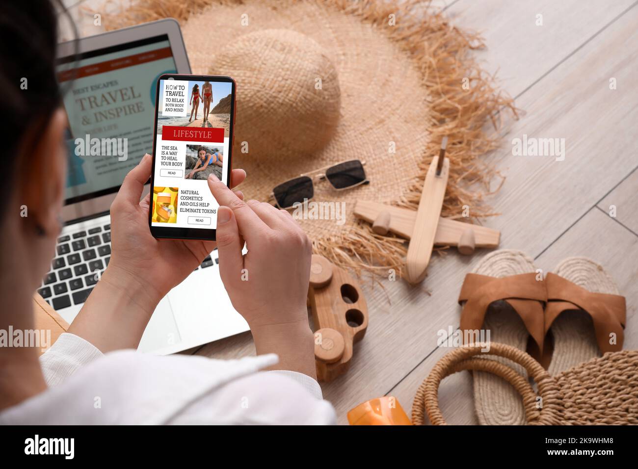 Female travel blogger using mobile phone on light wooden floor, closeup ...