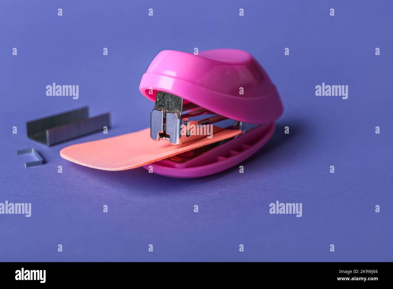Pink stapler with sticky notes on lilac background Stock Photo - Alamy