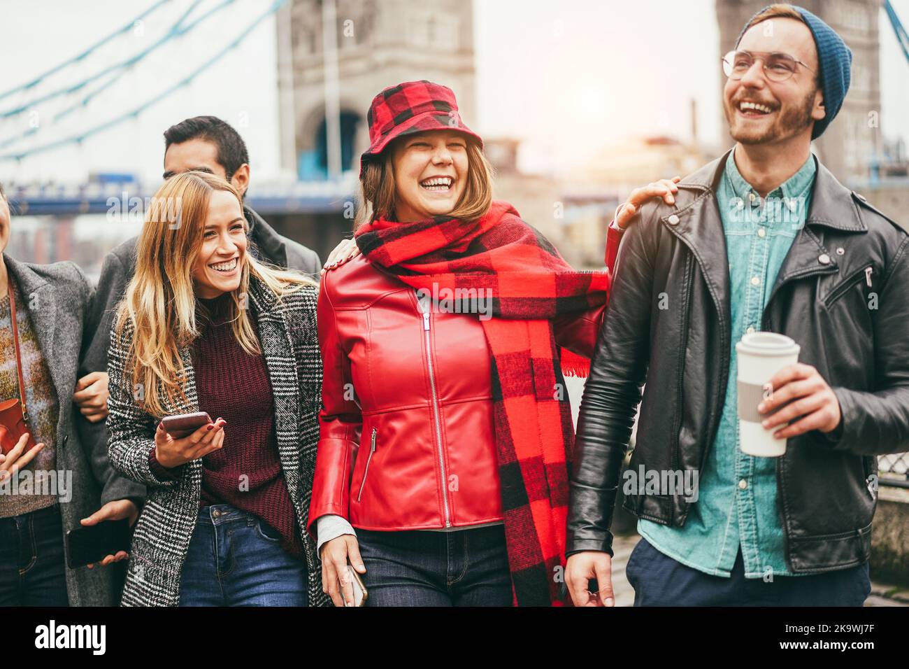 Young friends having fun outdoor at the city with Tower Bridge in London in background - Focus ...
