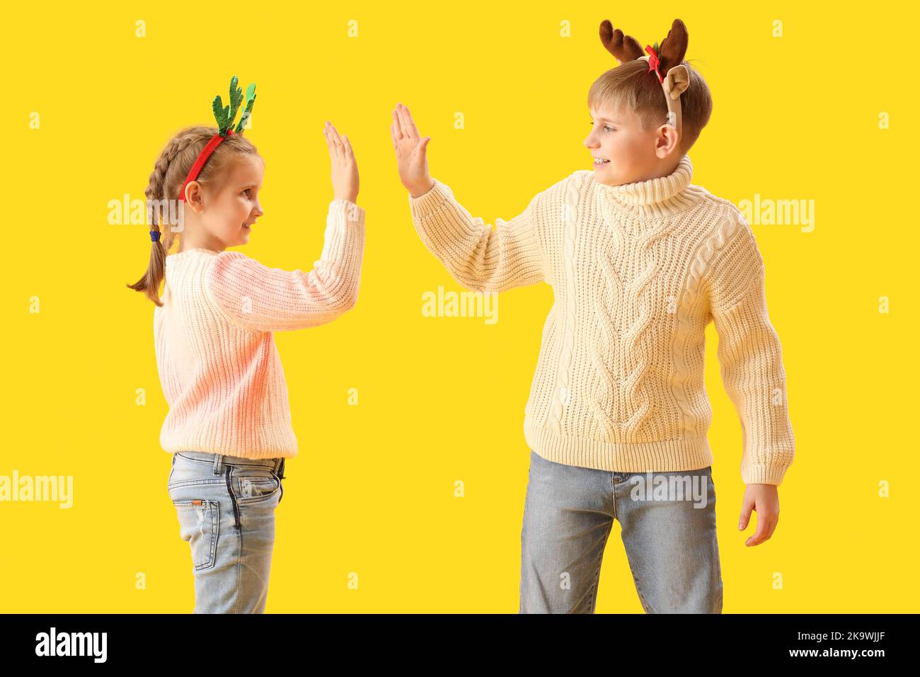 Happy little children in reindeer horns giving each other high-five on ...