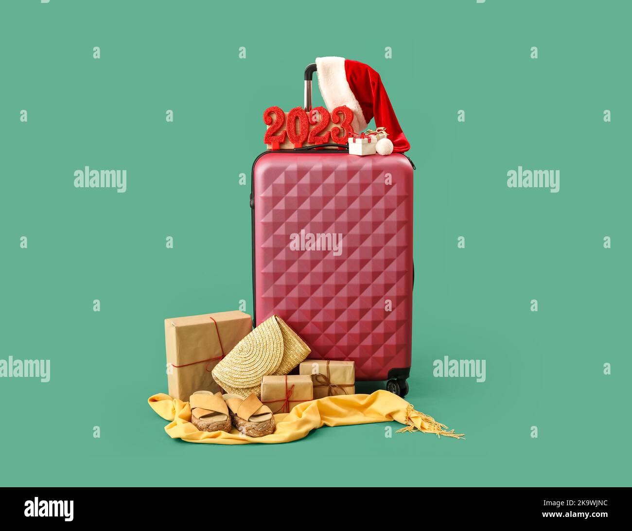 Suitcase with Santa hat, Christmas gifts and figure 2023 on green ...