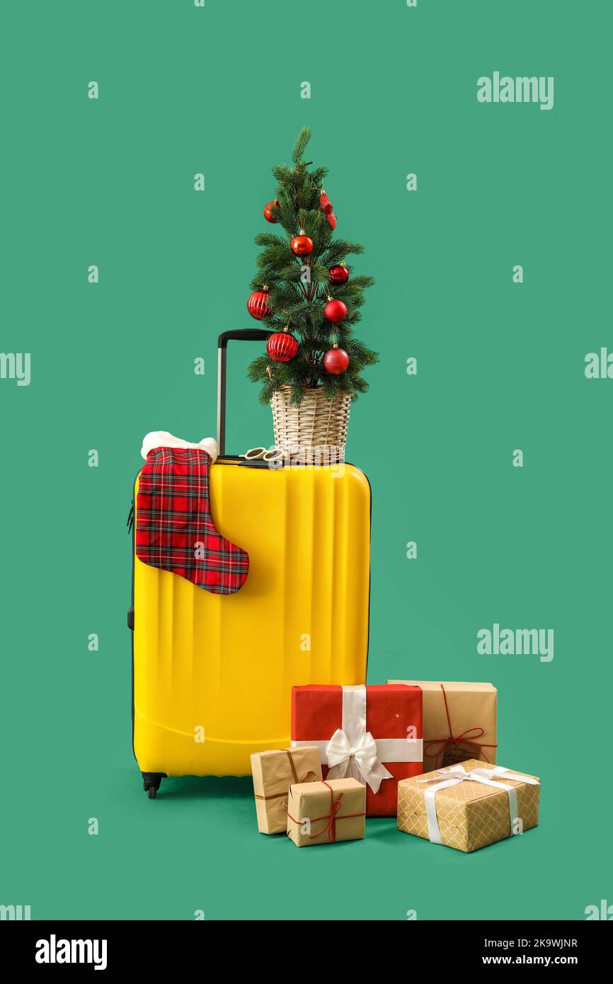 Suitcase with Christmas tree, sock and gifts on green background Stock ...