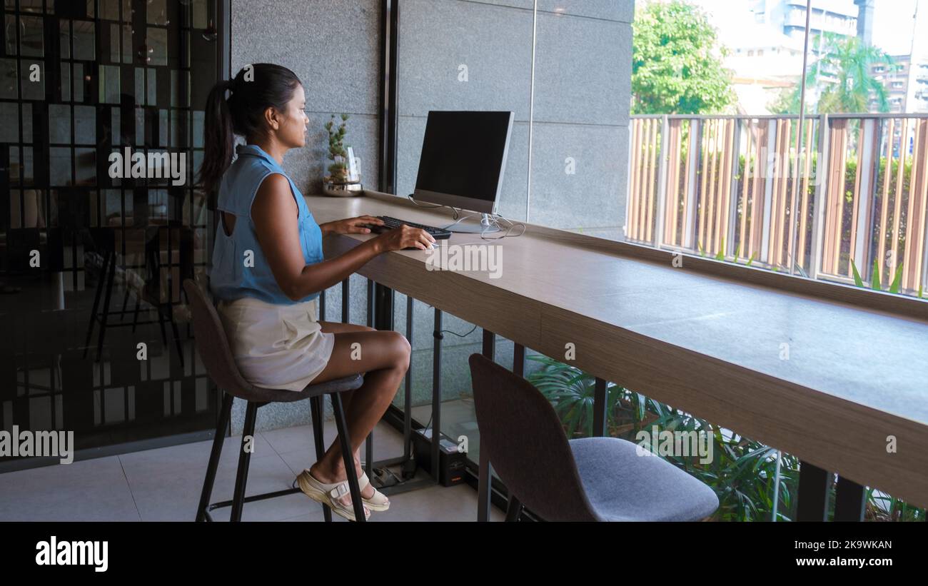 Thai Asian women working on a computer desk in a hotel lobby. Women ...