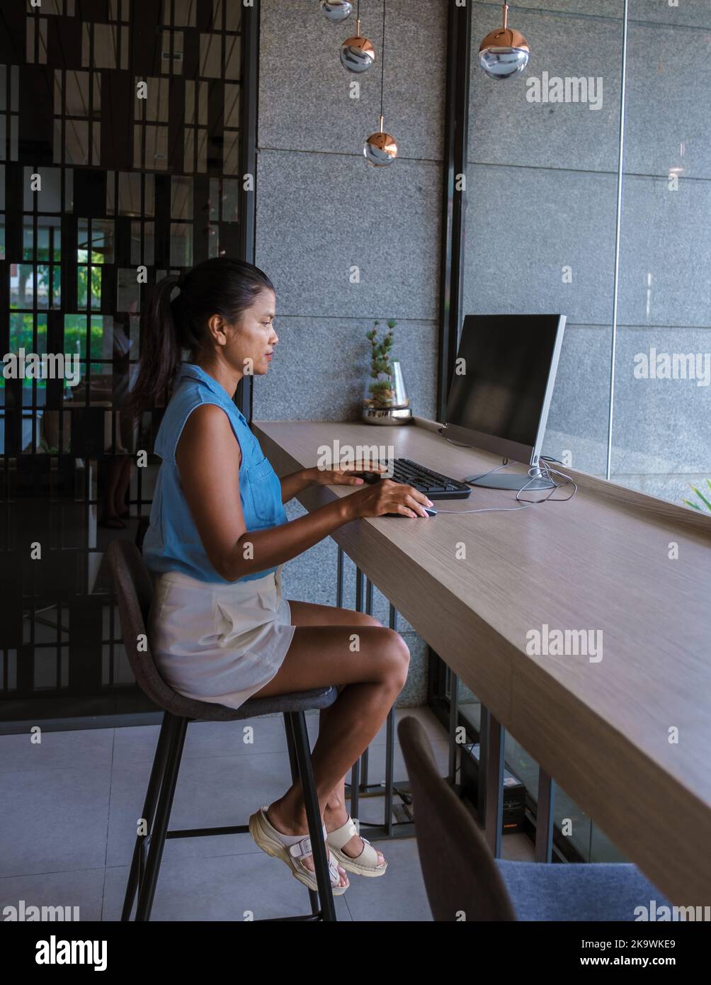 Thai Asian women working on a computer desk in a hotel lobby. Women ...