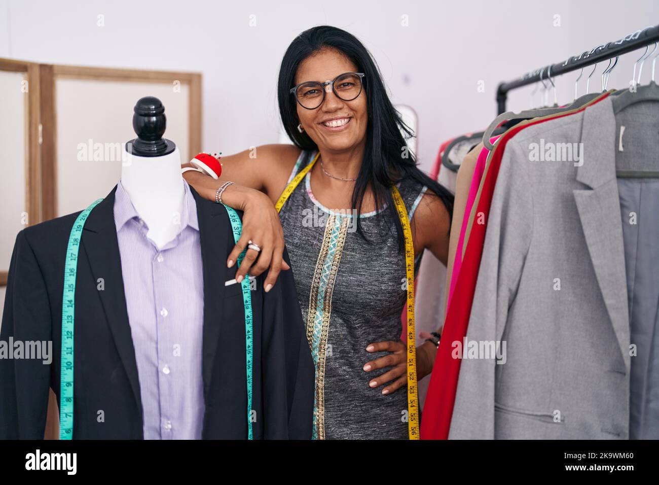Middle age hispanic woman tailor smiling confident leaning on manikin ...