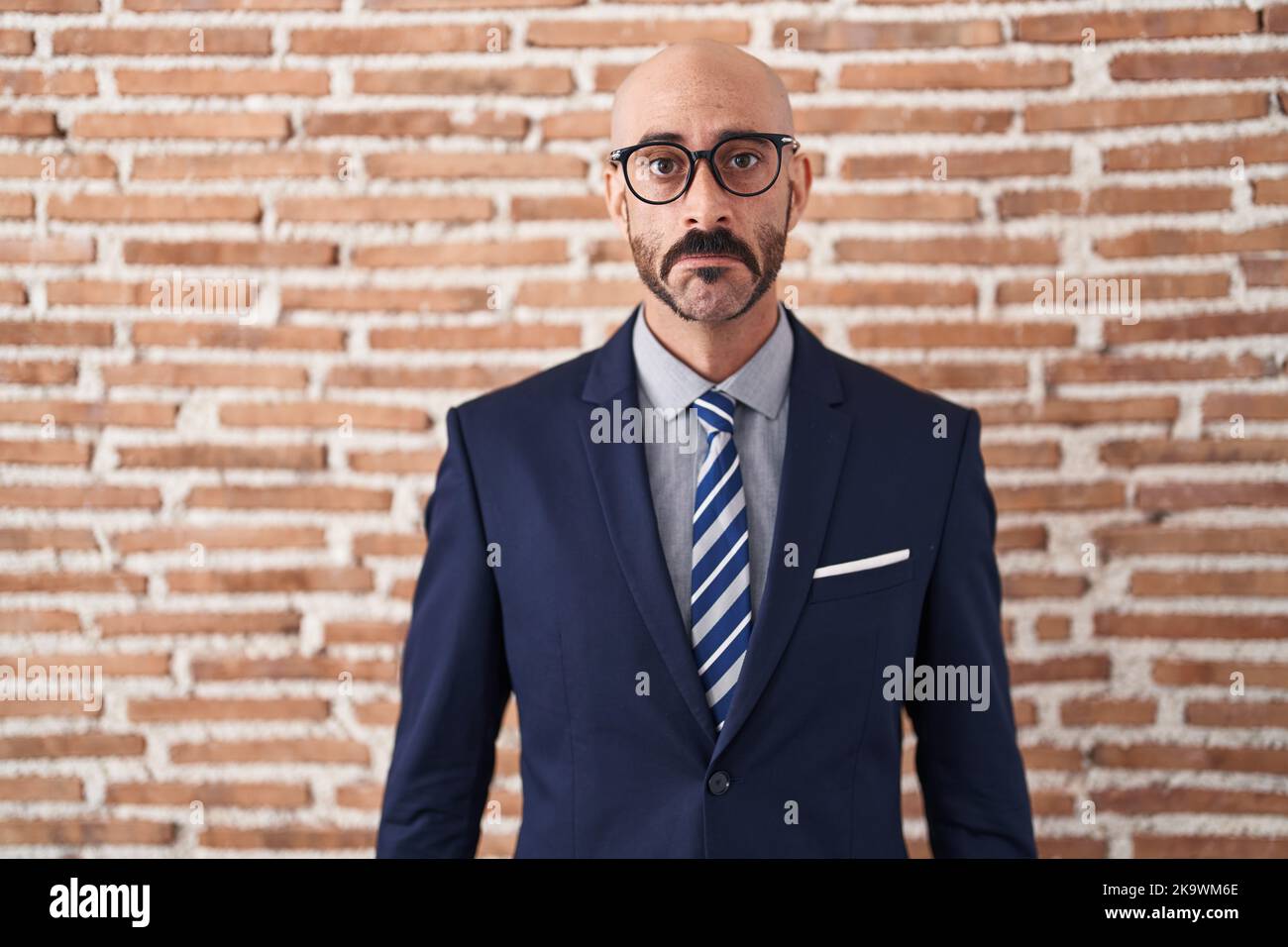 Bald man with beard wearing business clothes and glasses depressed and ...
