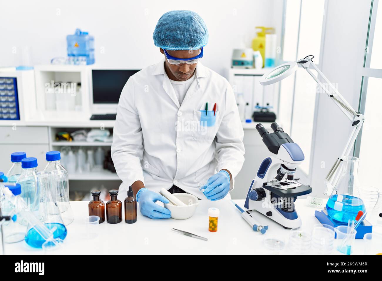 Young south east man wearing scientist uniform making experiment at ...