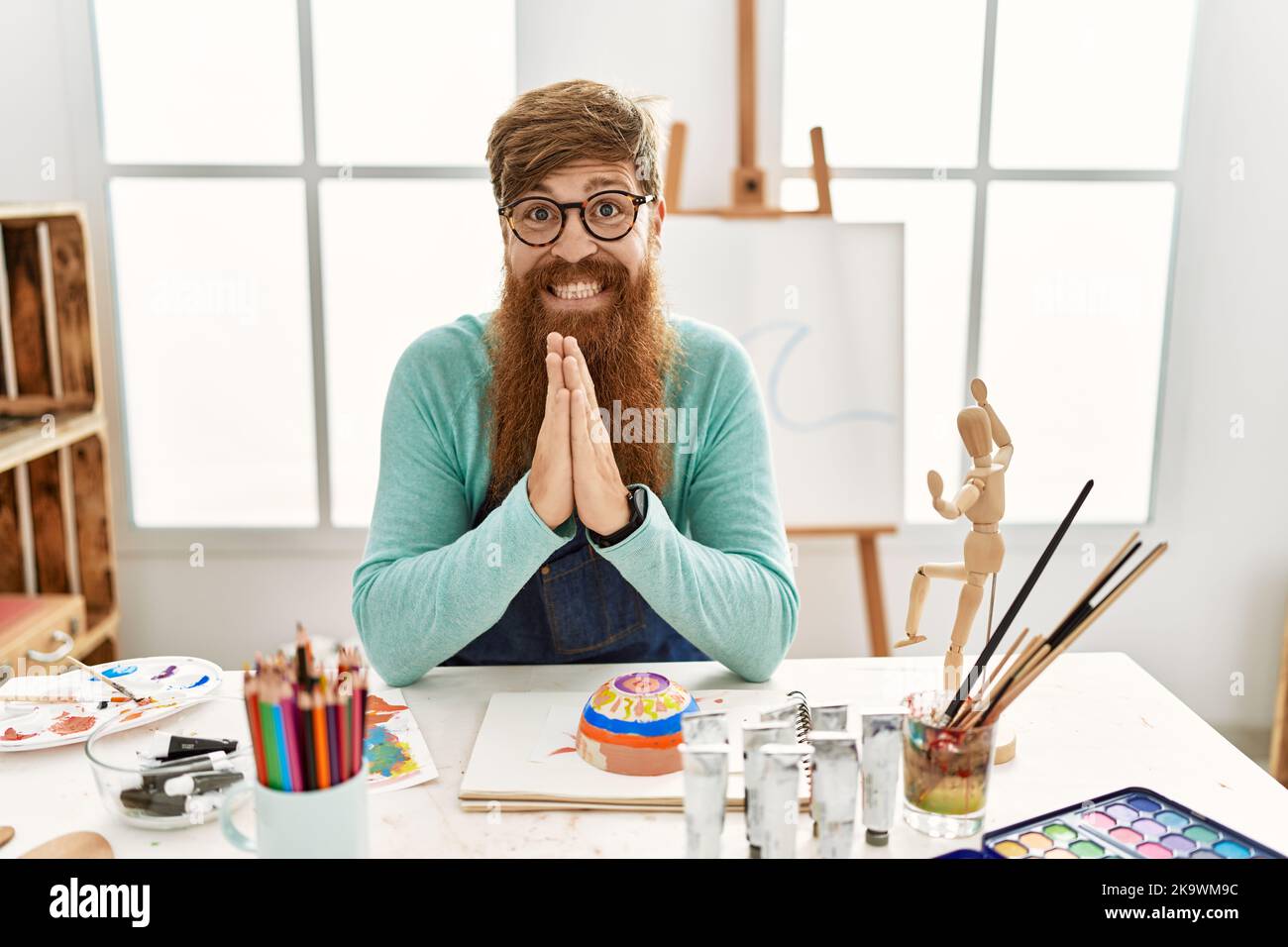 Redhead man with long beard painting clay bowl at art studio praying ...