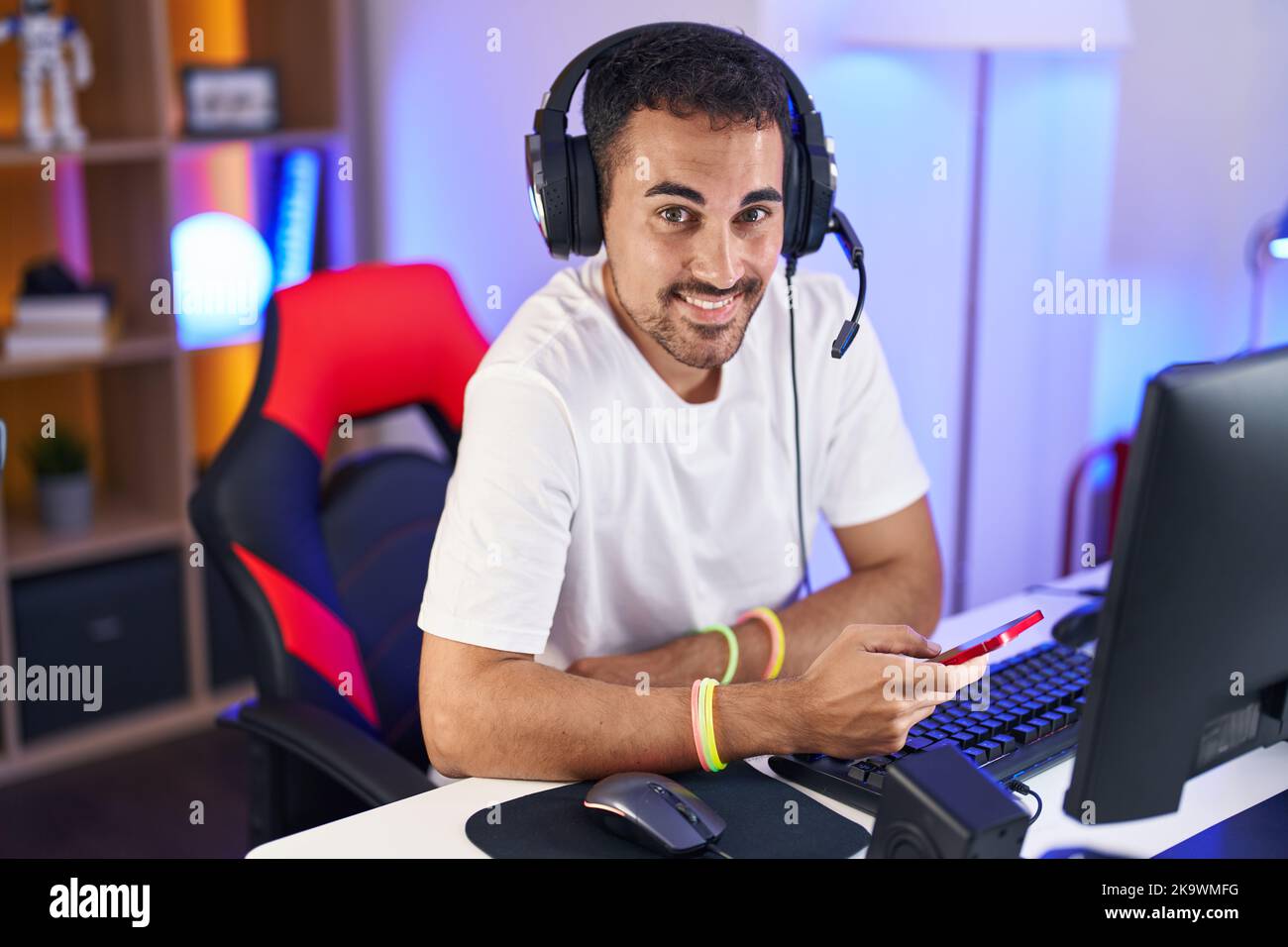 Young hispanic man streamer using computer and smartphone at gaming ...