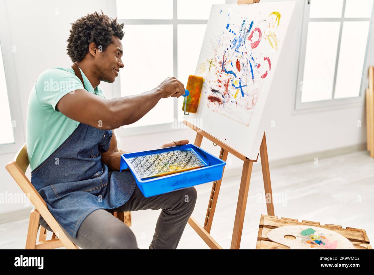 Young african american artist man drawing using paint roller at art ...