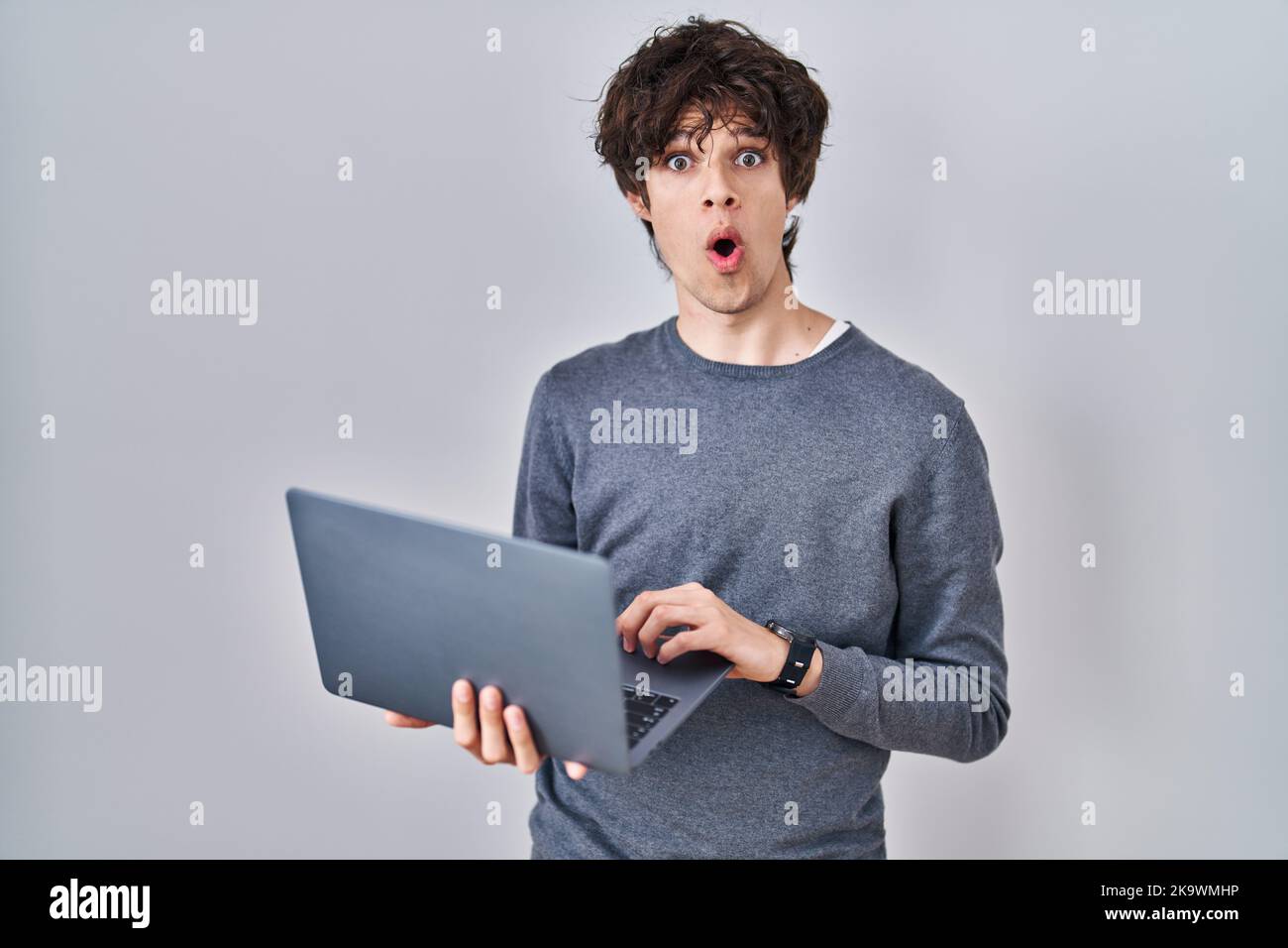 Young man working using computer laptop scared and amazed with open ...