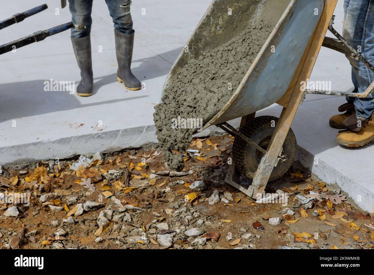 Construction worker pouring cement from wheelbarrow onto to create new ...