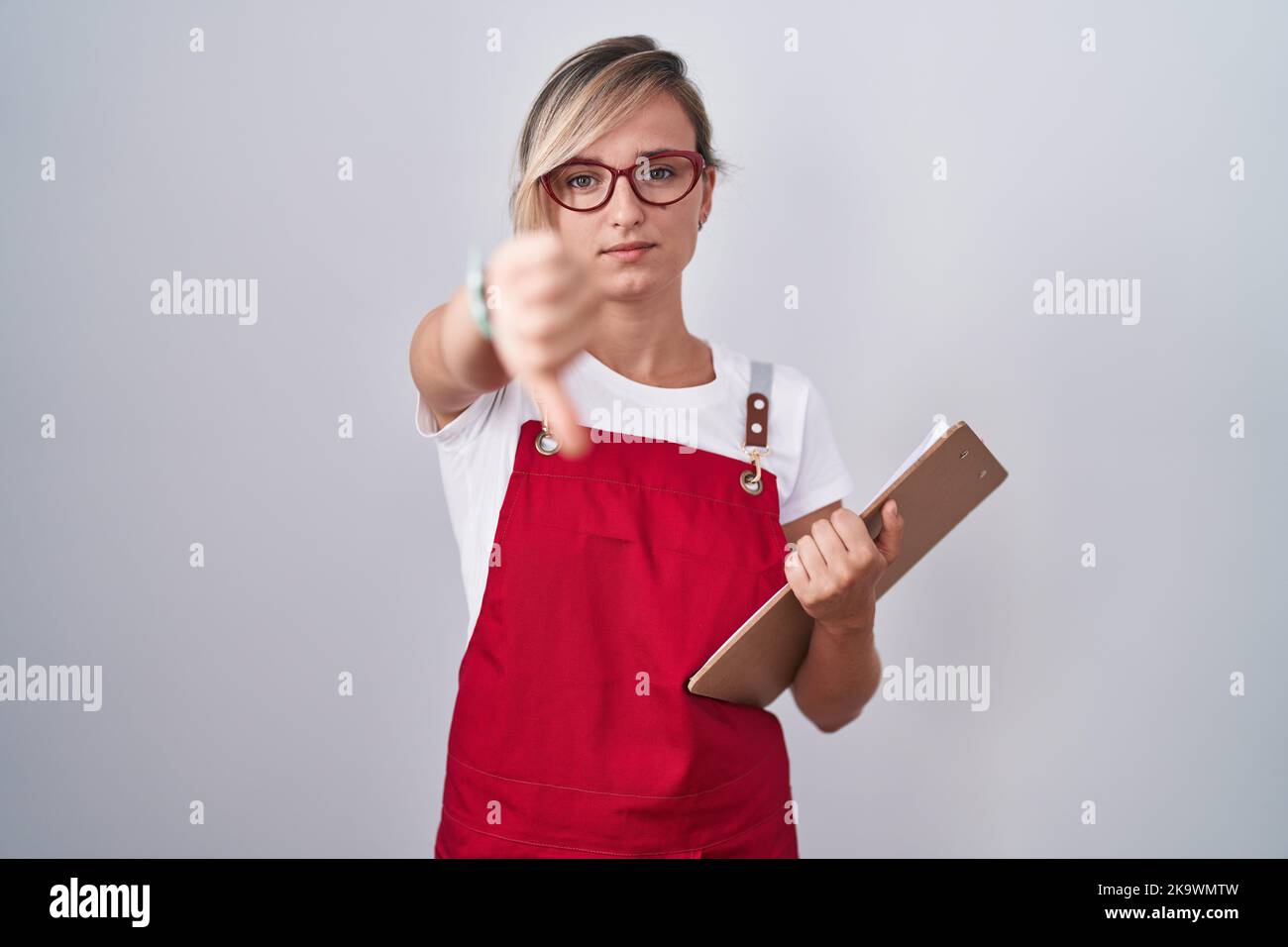 Young blonde woman wearing waiter uniform holding clipboard looking ...