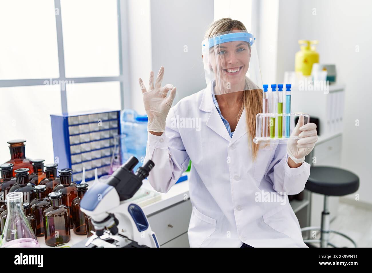 Beautiful woman working at scientist laboratory doing ok sign with ...