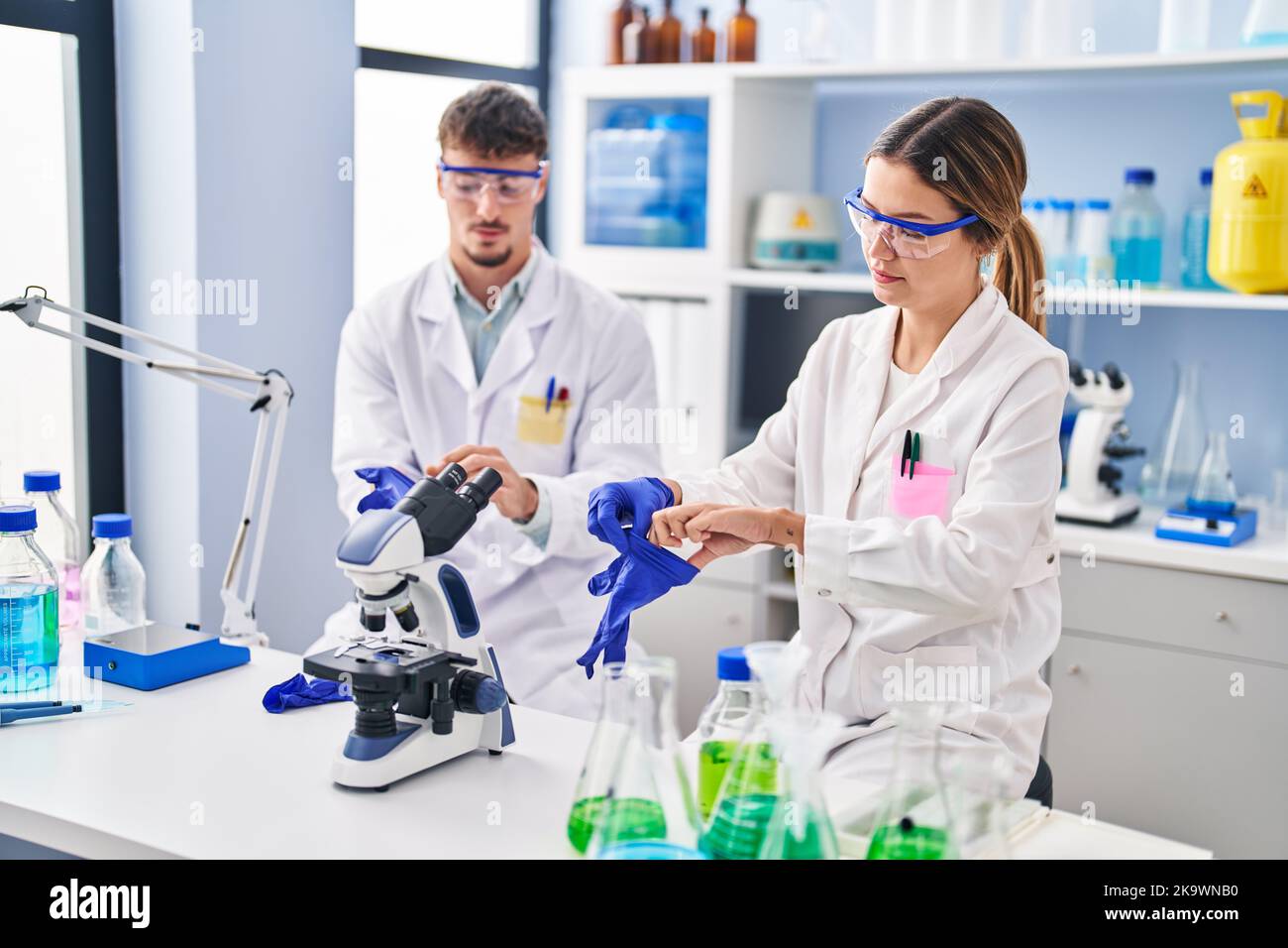 Young man and woman scientists workers wearing gloves at laboratory ...