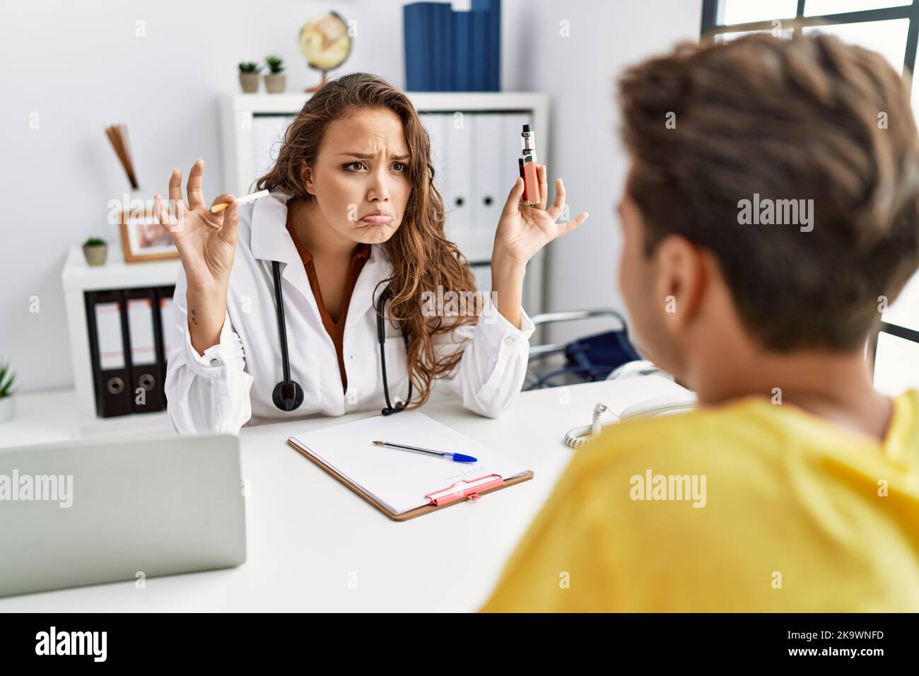 Young doctor woman showing electronic cigarette and normal cigarrete to ...
