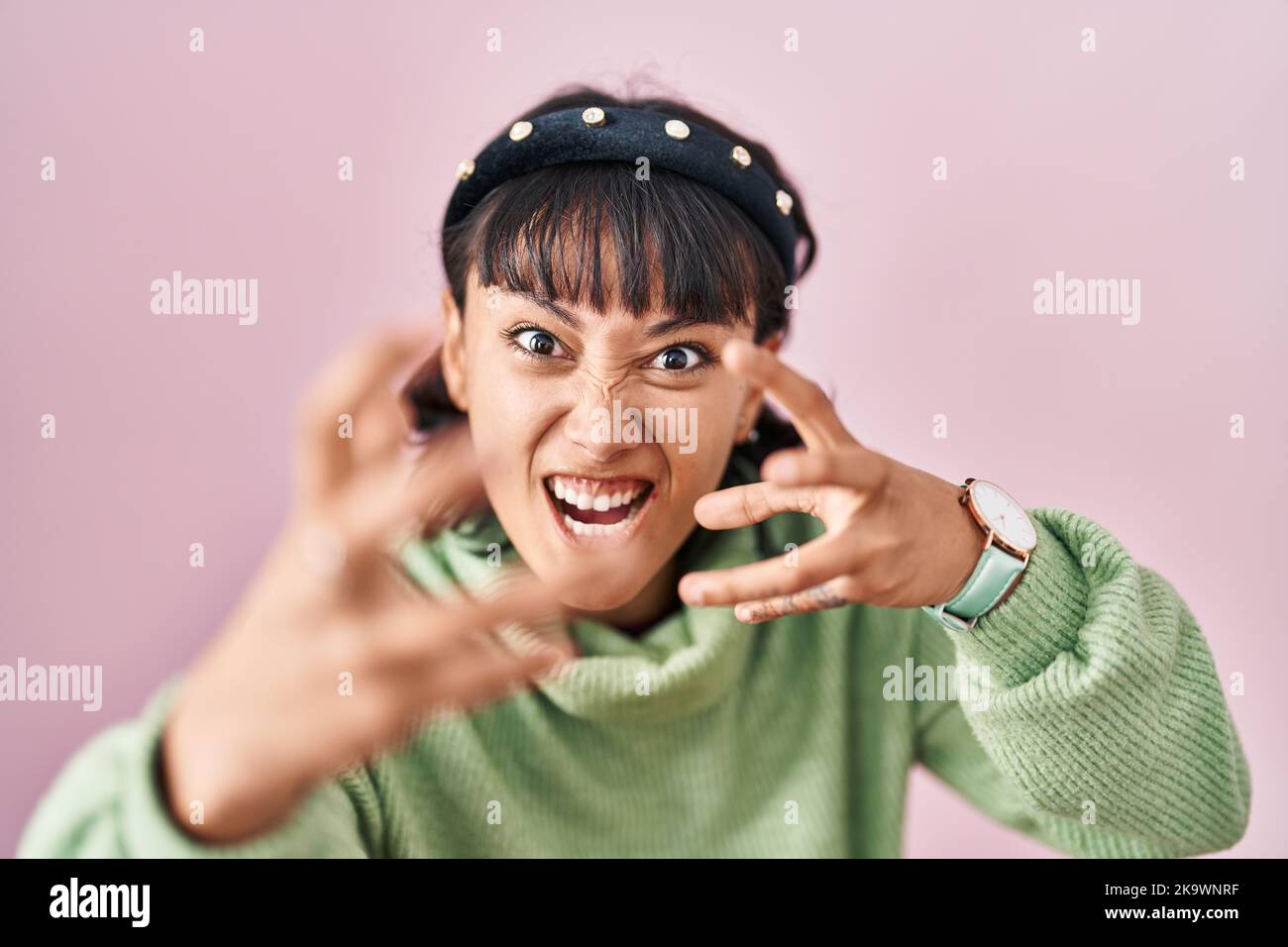 Young beautiful woman standing over pink background shouting frustrated ...