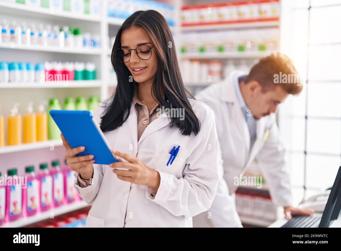 Man and woman pharmacists using touchpad and computer working at ...