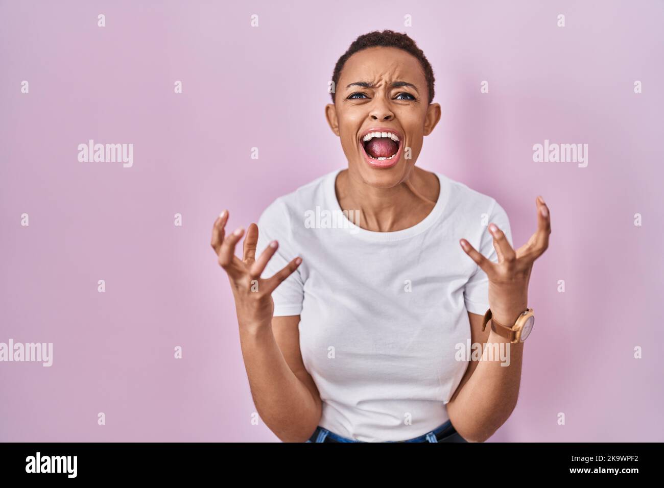 Beautiful african american woman standing over pink background crazy ...